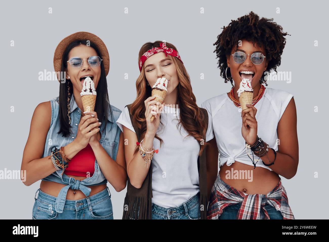 Three attractive young women eating ice cream and smiling while ...