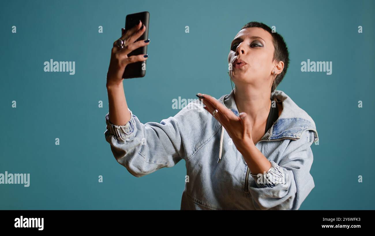 Silly stylish girl filming a video on her phone while she dances ...