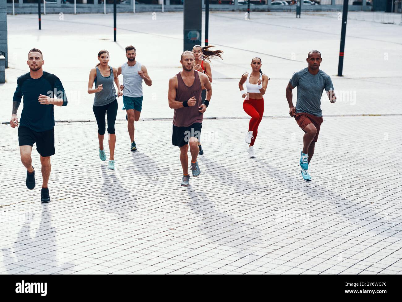 Full length of people in sports clothing jogging while exercising on ...