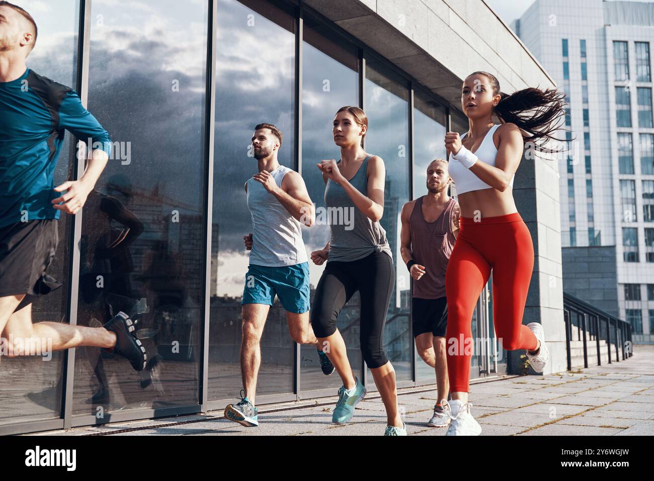 Group of people in sports clothing jogging while exercising on the ...