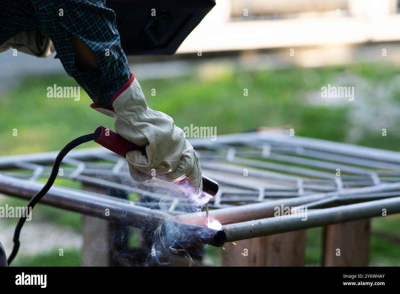 Close up of a welder welding metal frame outdoors Stock Photo - Alamy