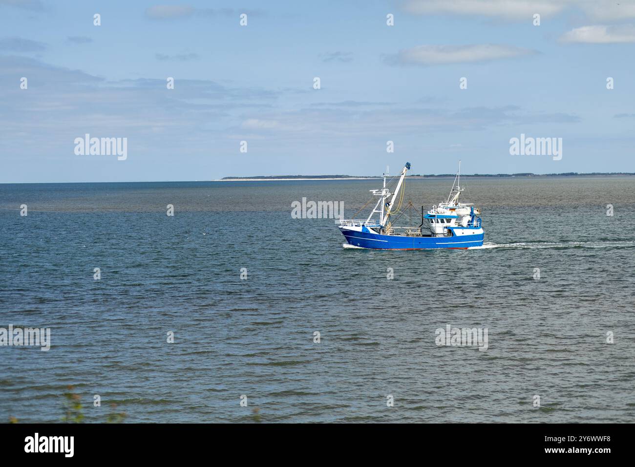 A fishing boat glides across calm waters, surrounded by a picturesque ...