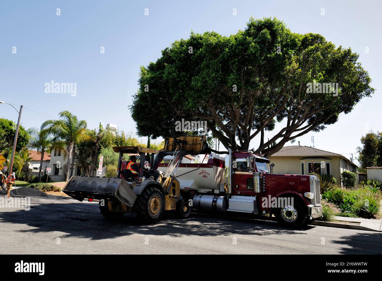 Street undergoing resurfacing with workers and machinery actively ...