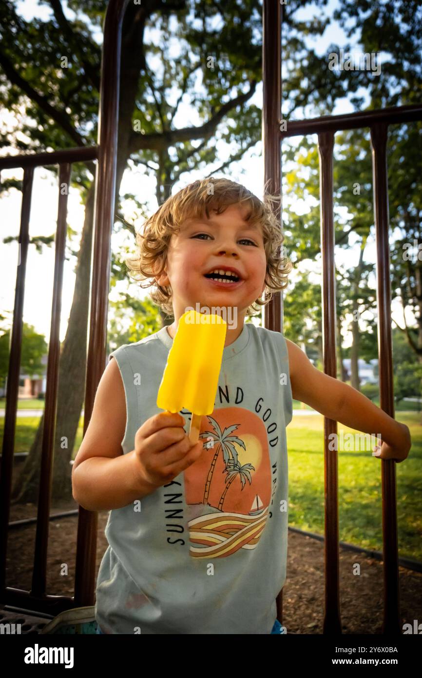 young child eating yellow popsicle outside on playground Stock Photo ...