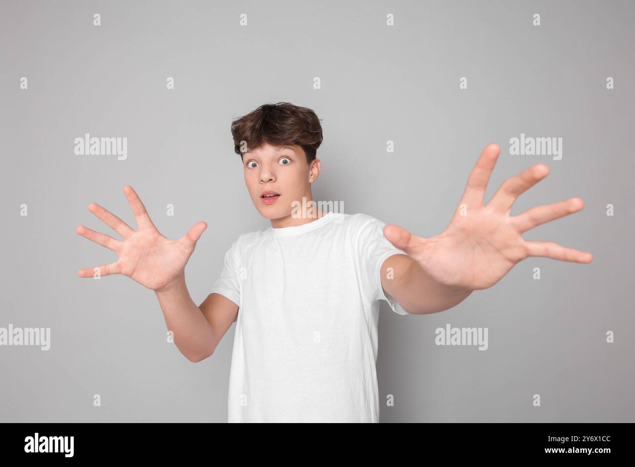 Portrait of scared teenage boy on grey background Stock Photo - Alamy