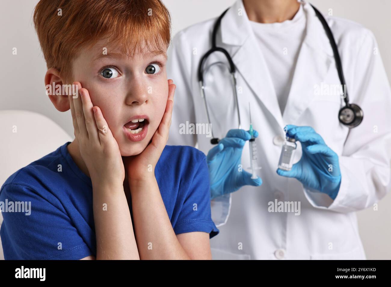 Dental phobia. Scared boy near dentist with syringe and vial on light grey background Stock ...