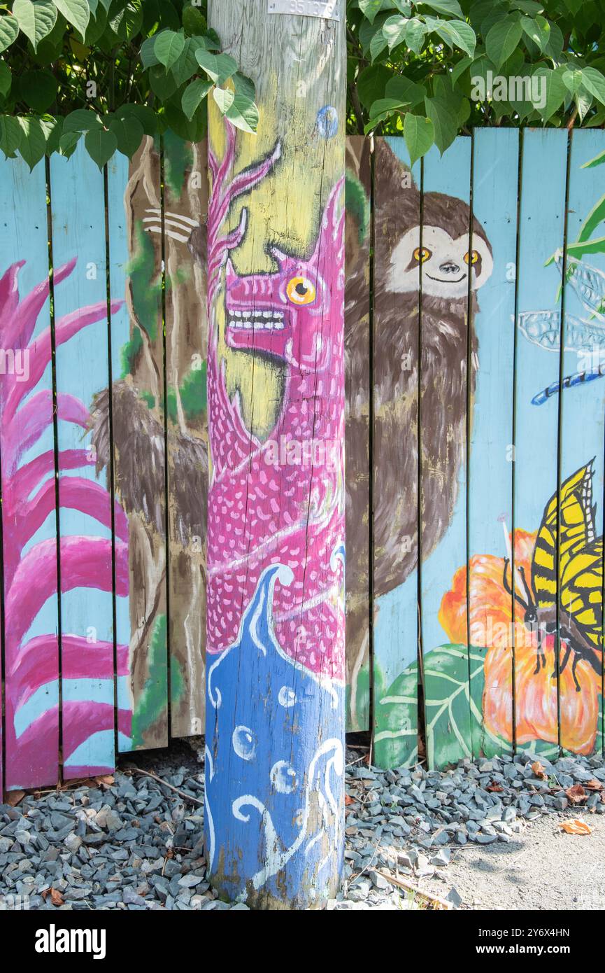 Mural toucan, sloth and iguana on a wooden fence and utility pole in ...