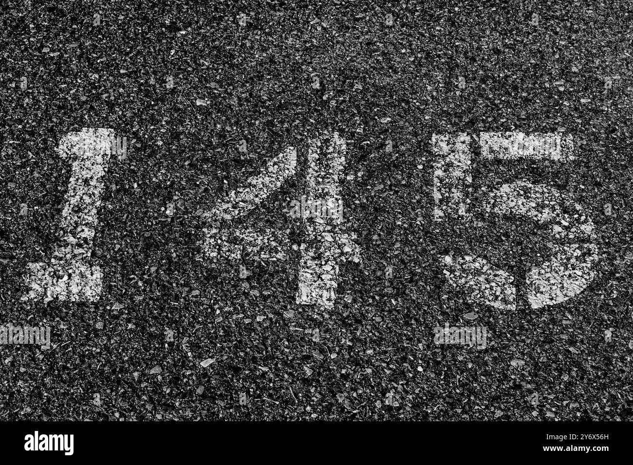 The number 145 stenciled in white on the dark rough pavement of an ...