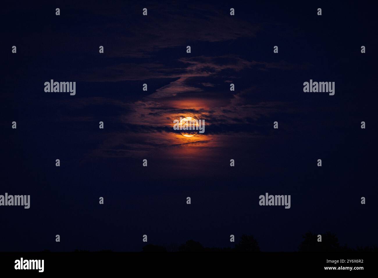 Harvest Moon shining in between the bands of dark clouds Stock Photo ...