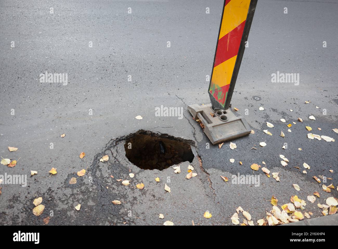 Details with a big pothole in the middle of a paved road with cars ...