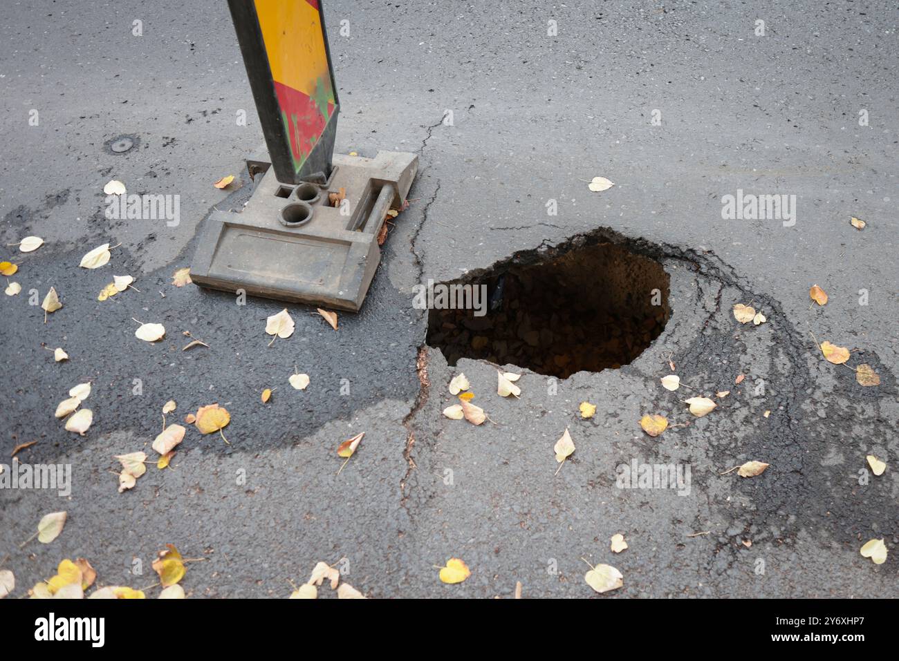 Details with a big pothole in the middle of a paved road with cars ...