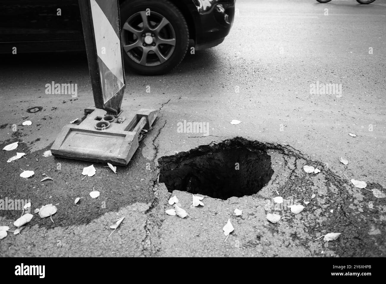 Details with a big pothole in the middle of a paved road with cars ...