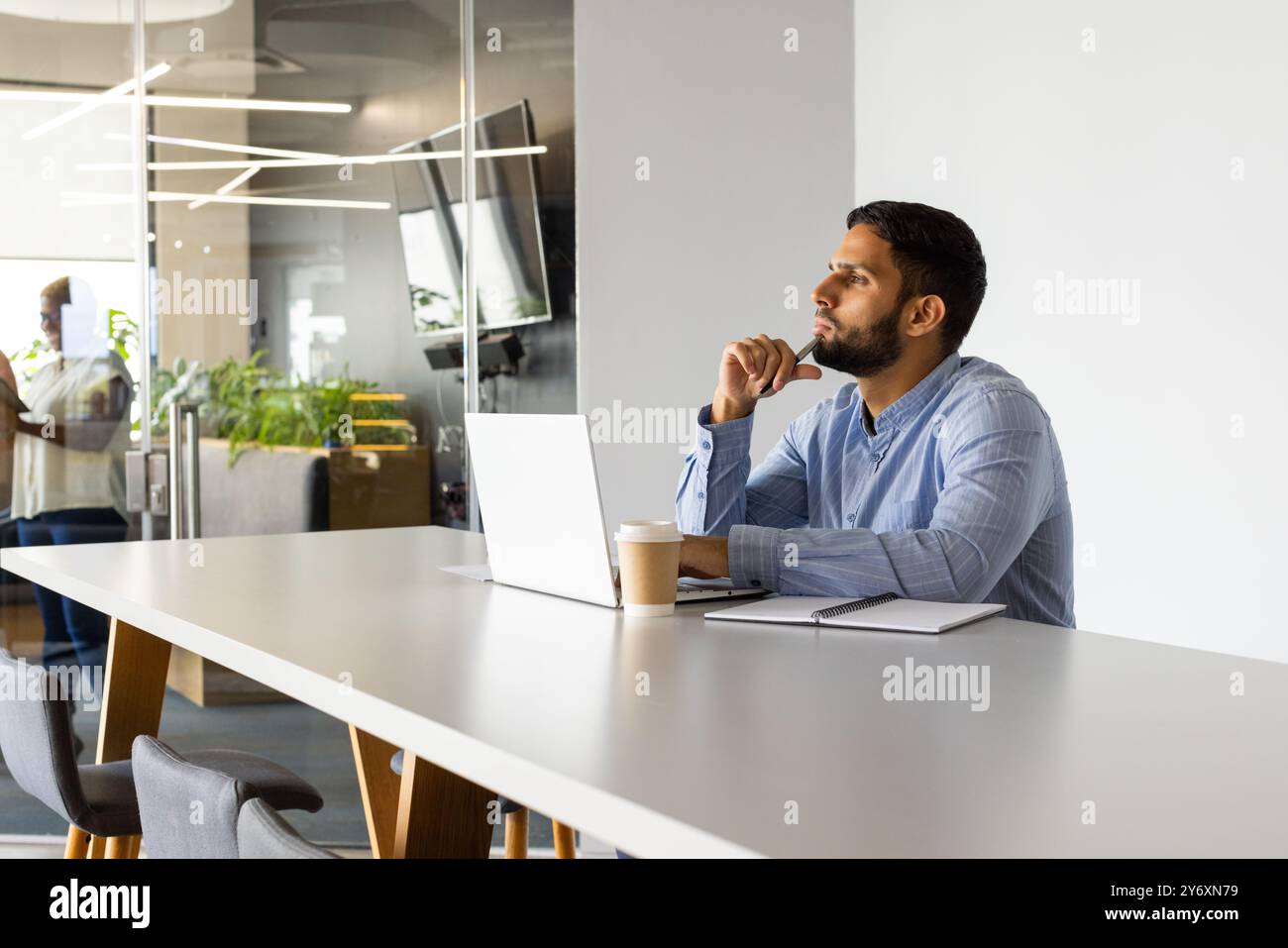 Thinking deeply, man working on laptop with coffee cup in modern office ...
