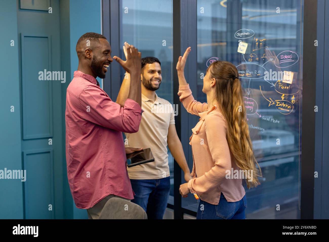 High-fiving, diverse colleagues celebrating successful project in ...