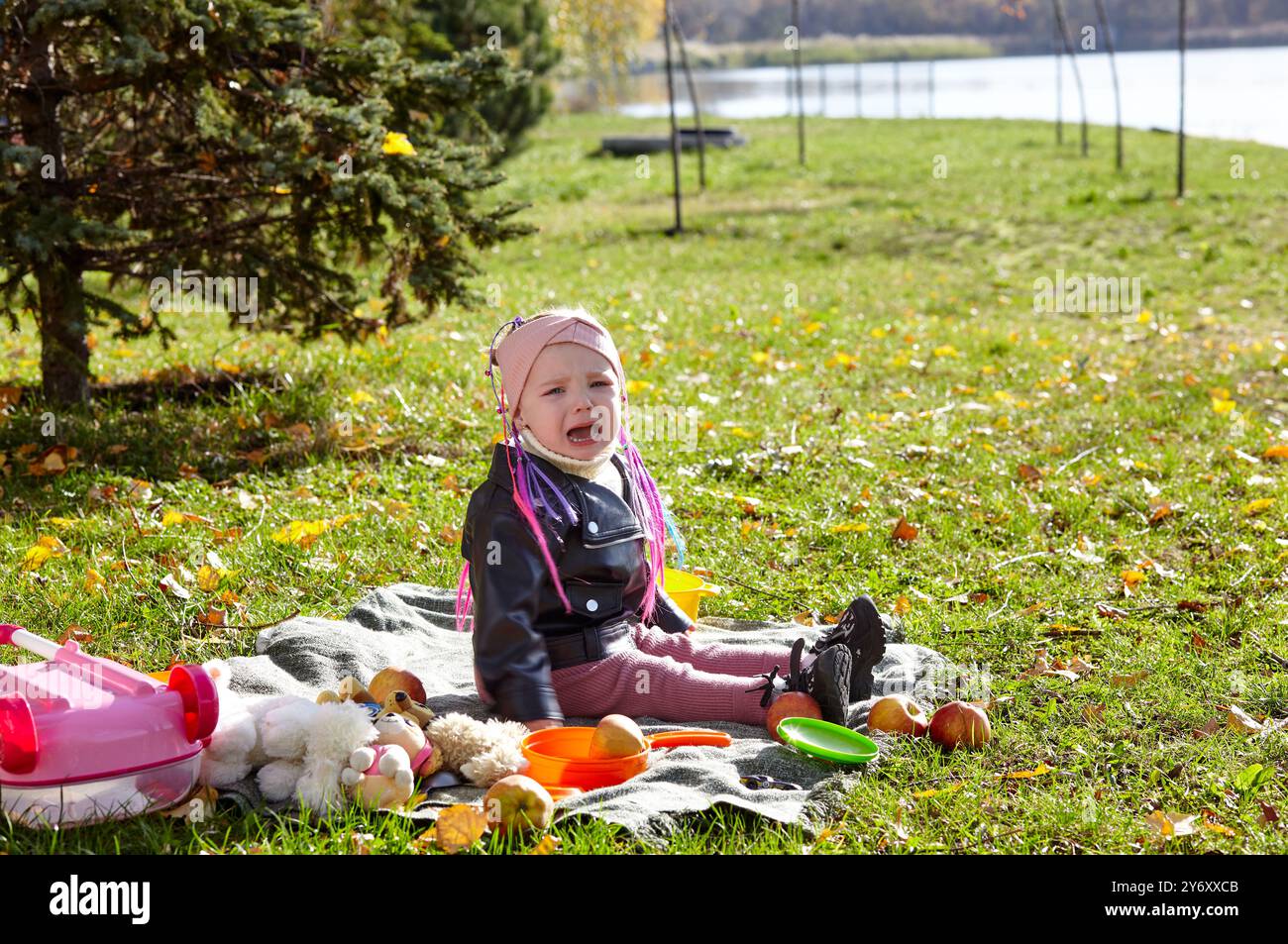 The baby child is crying. Baby on plaid in autumn city park. Sad child ...