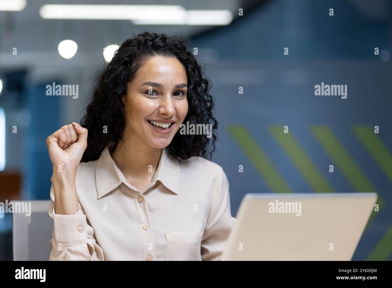 Happy professional woman in office showing success gesture while using ...