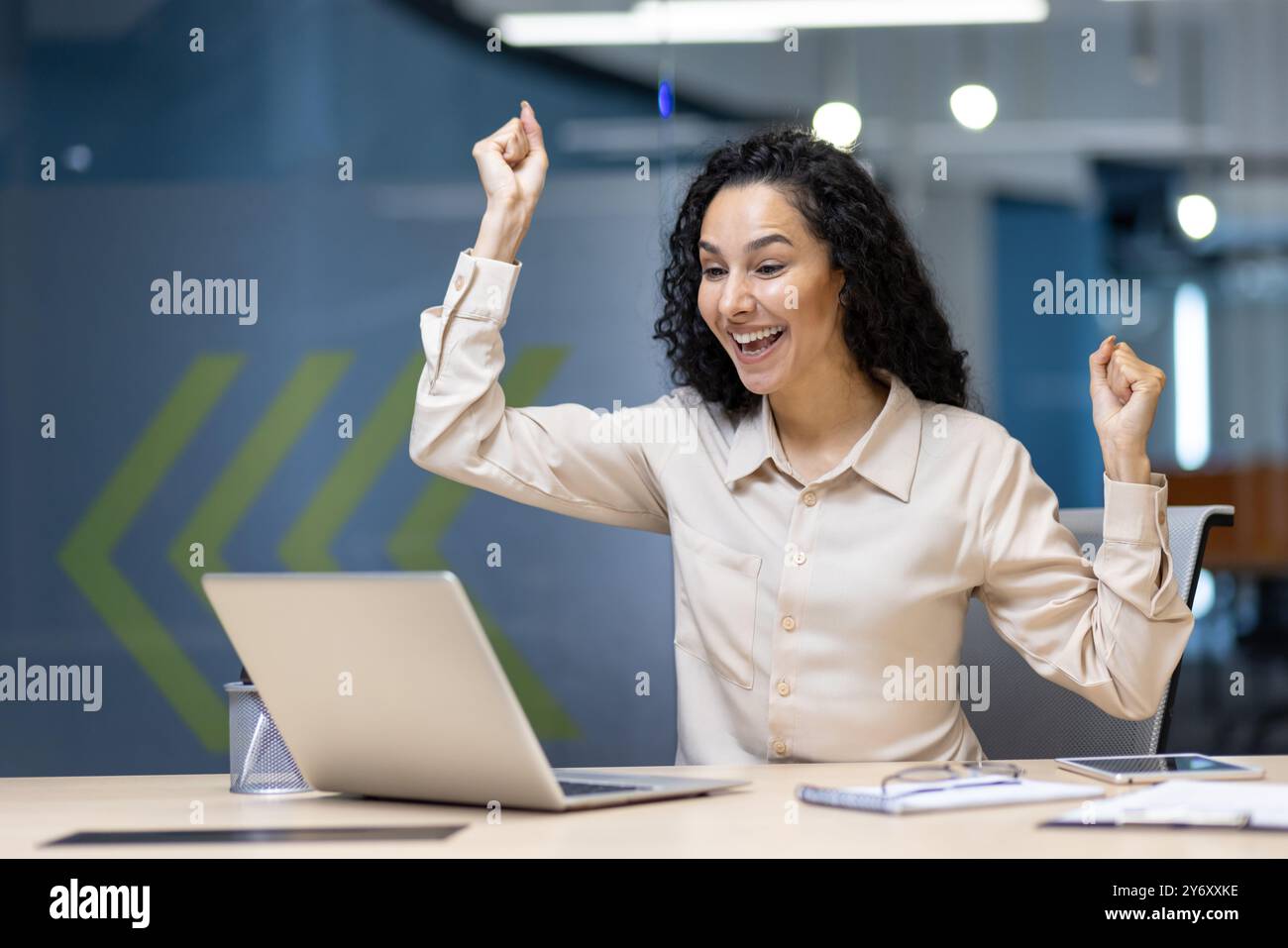 Businesswoman expressing excitement while working on laptop in modern ...