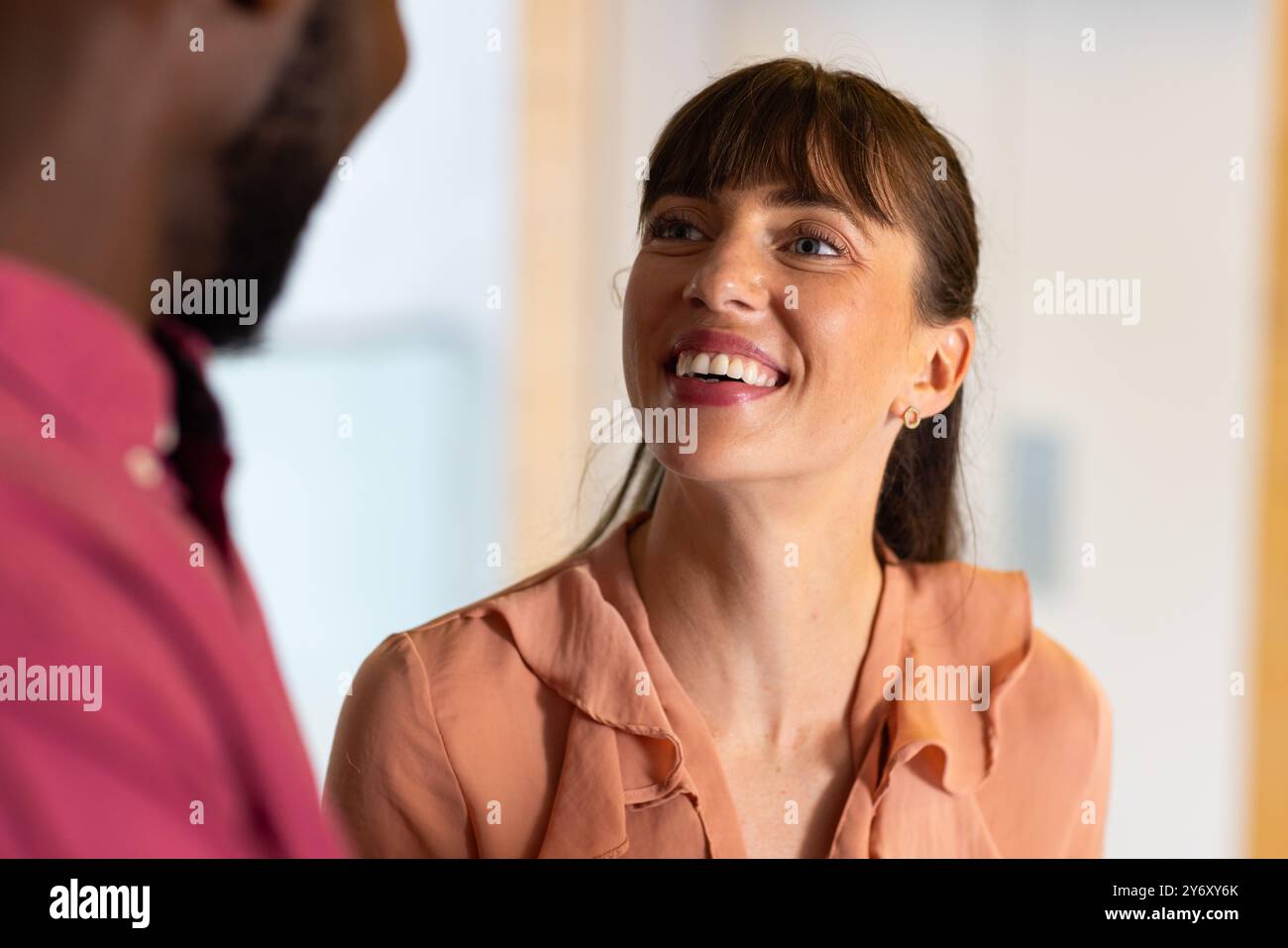 Smiling woman engaging in conversation with colleague in office setting ...