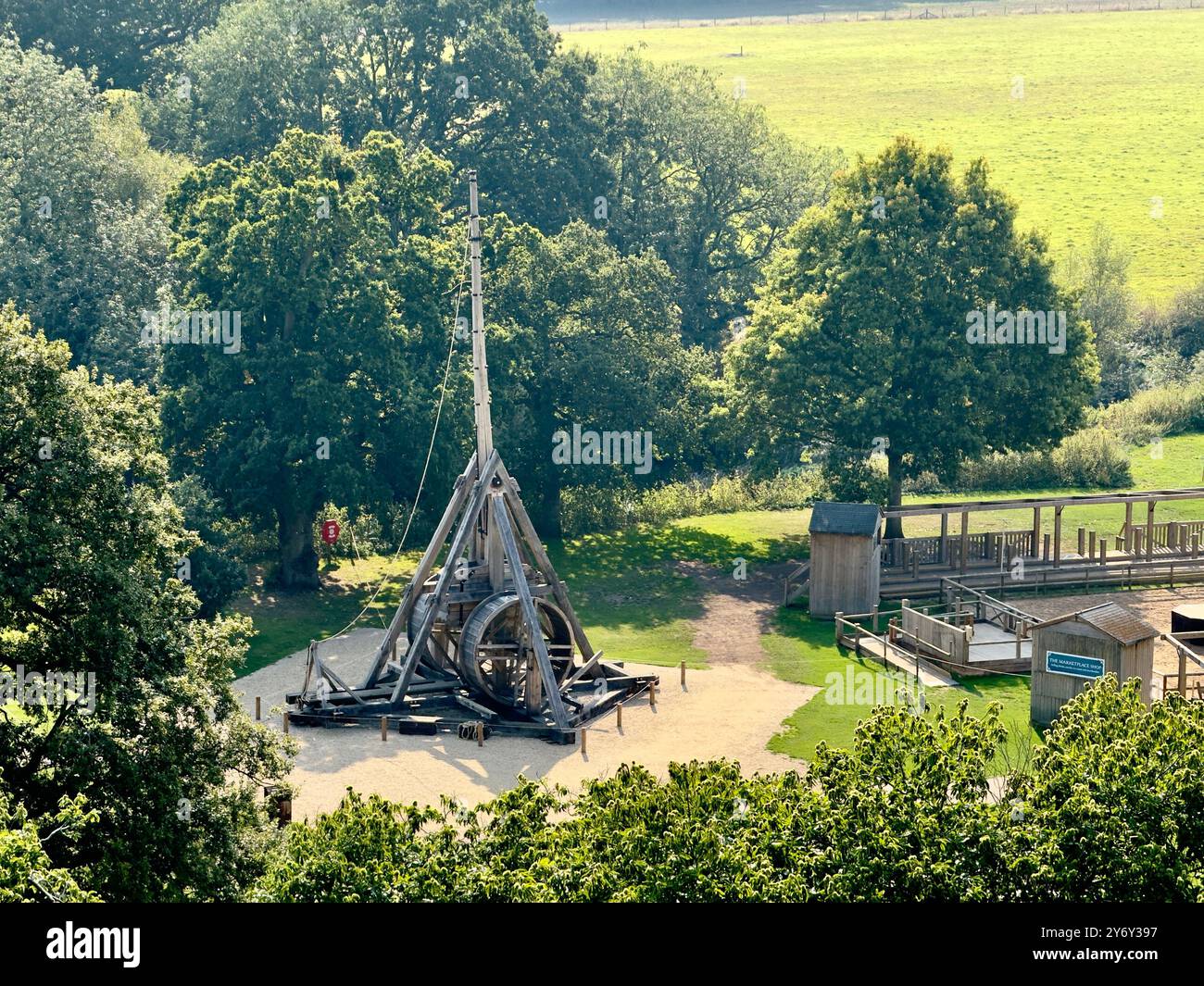 A large medieval trebuchet surrounded by lush greenery in a historical ...