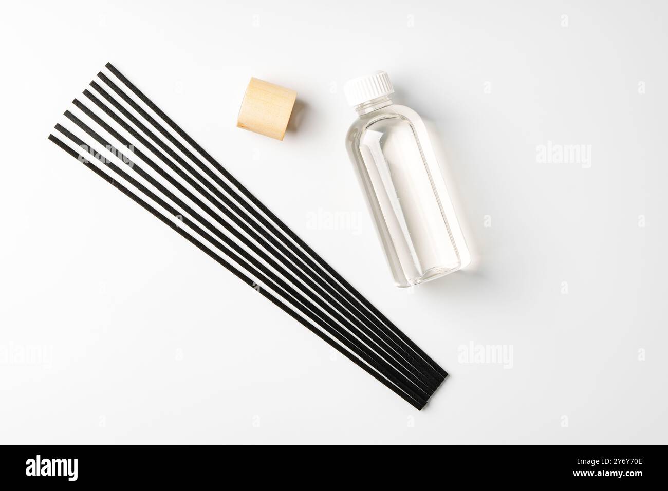 A minimalist display of essential oil and black diffuser sticks on a ...