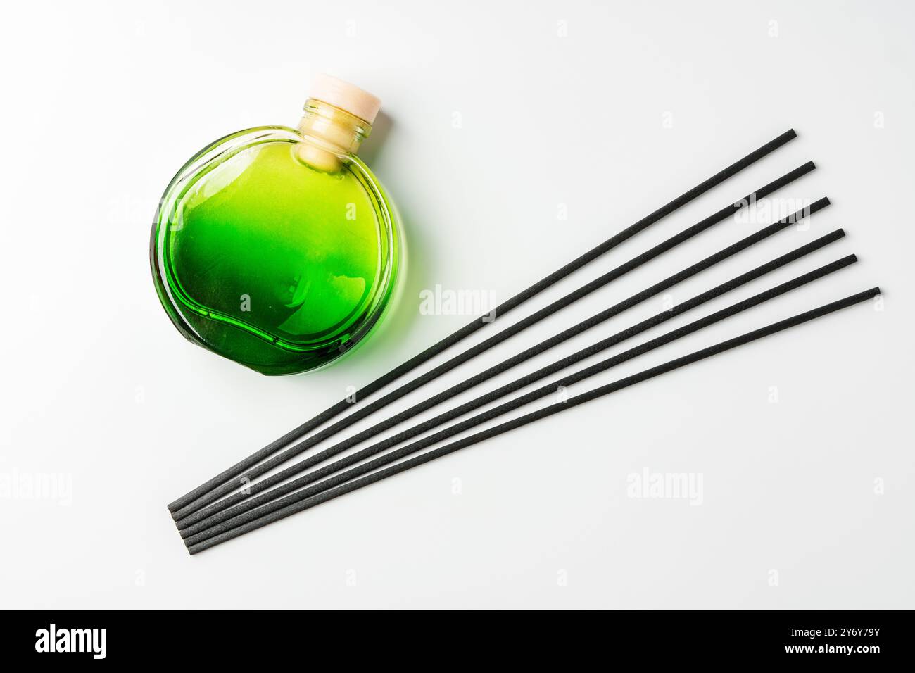 A minimalist display of essential oil and black diffuser sticks on a ...