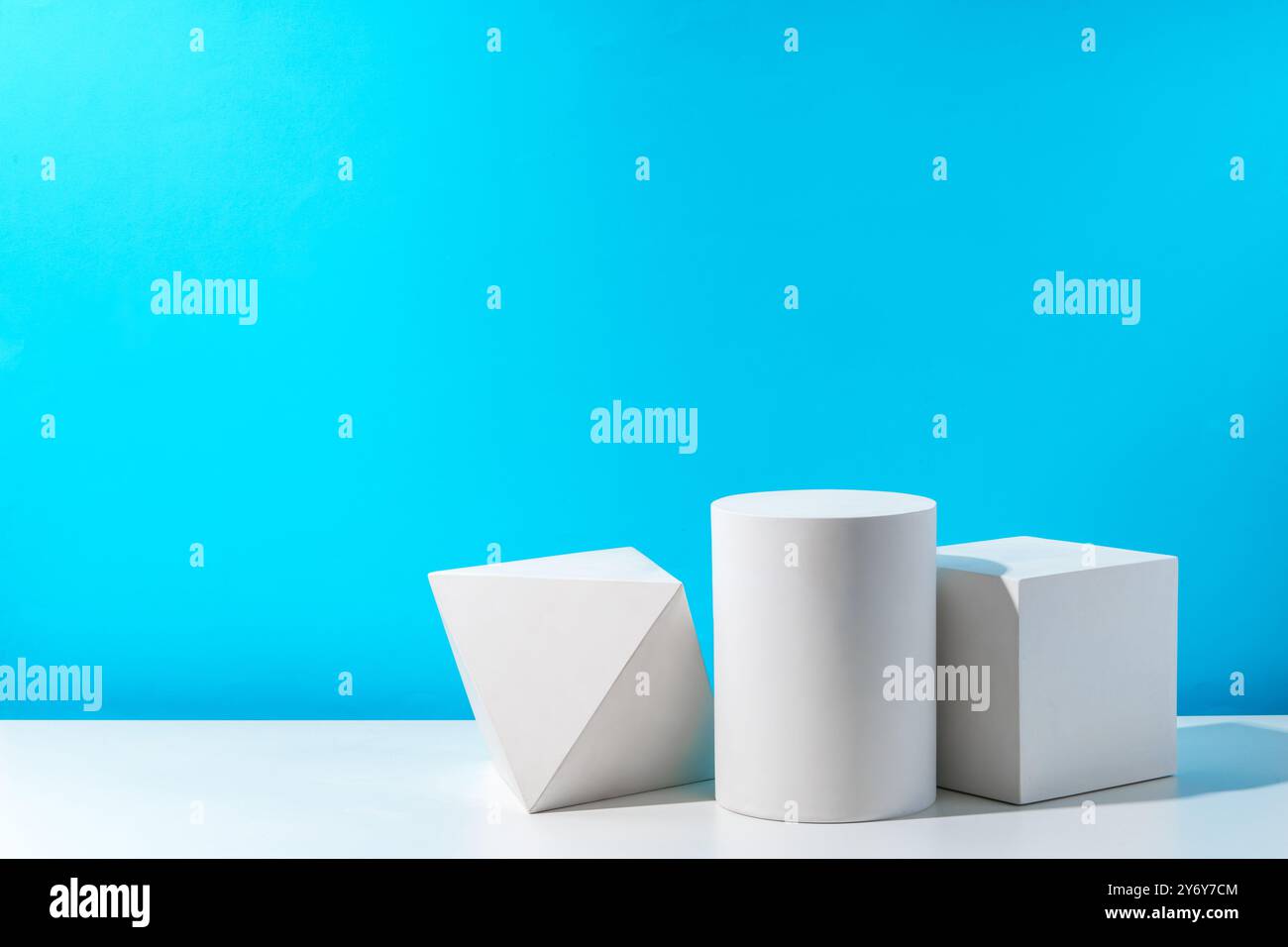 Three geometric shapes arranged on a table against a bright blue ...