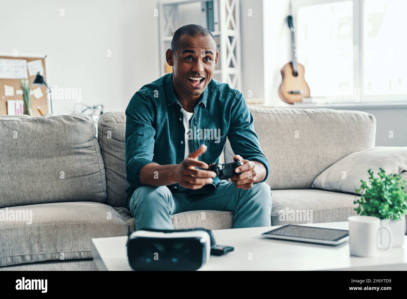 Modern gamer. Handsome young African man playing video game and smiling ...