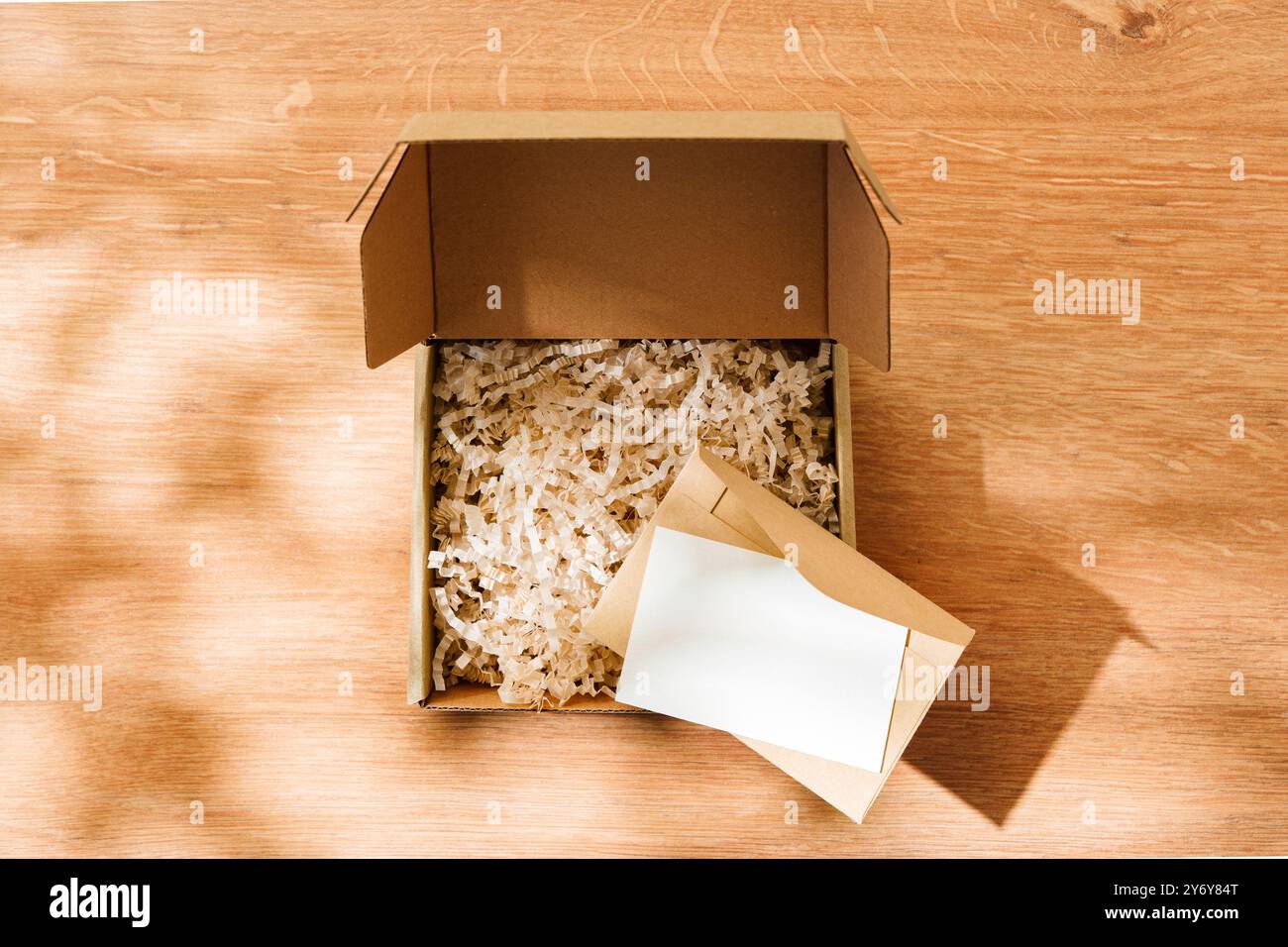 Open cardboard box filled with shredded paper and a blank card on a ...