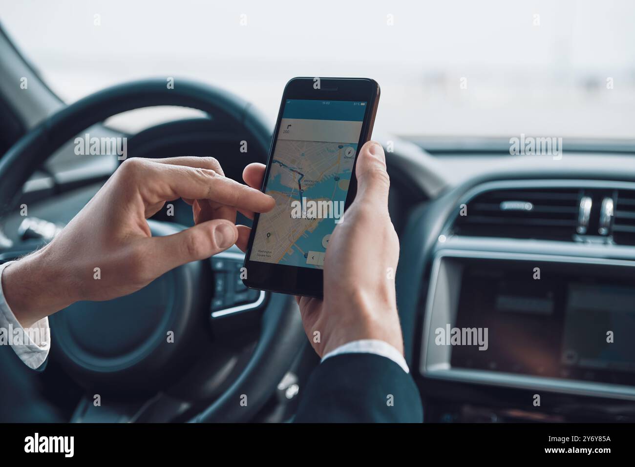 Checking the direction. Close up of young man using smart phone to ...