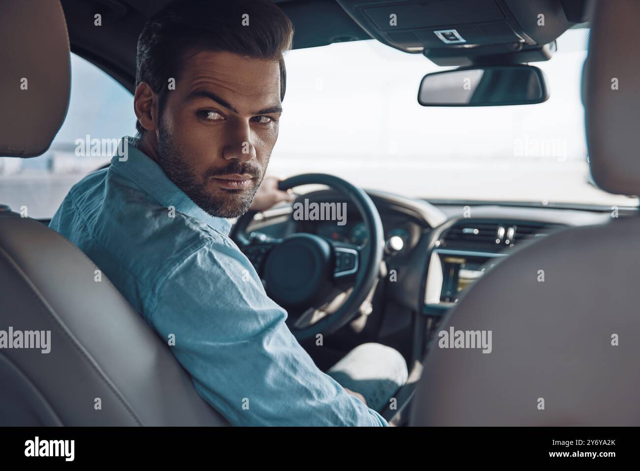 Ready to go? Rear view of young man in smart casual wear looking over ...