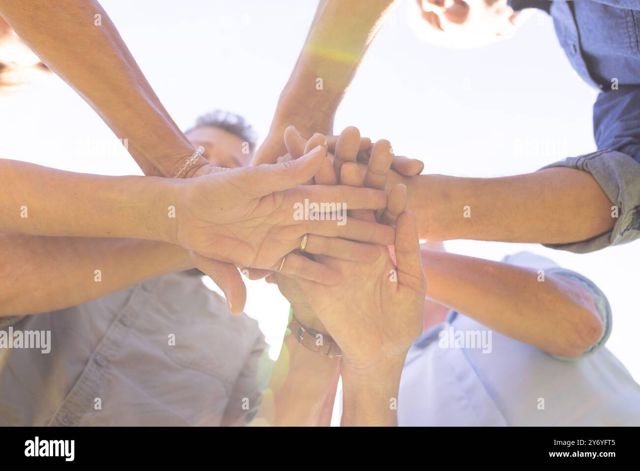 Senior diverse friends stacking hands together, showing unity and ...