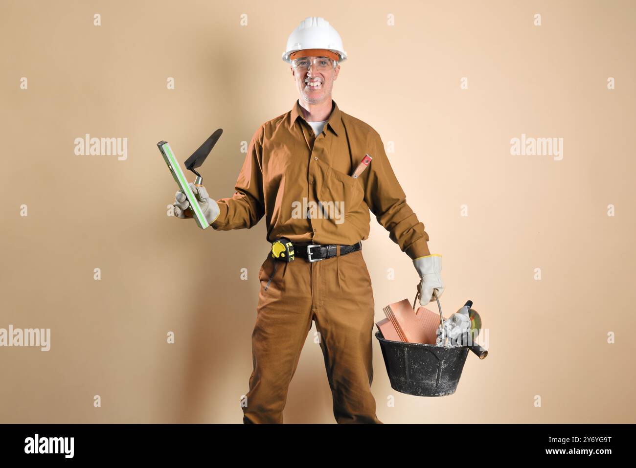 Construction worker dressed in work clothes holding tools and building ...
