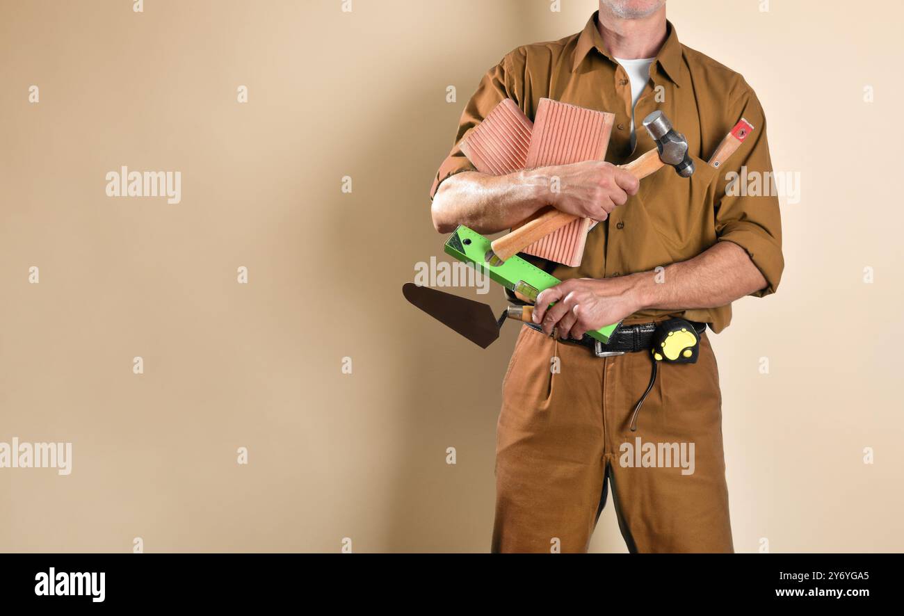Detail of mason dressed in work clothes equipped with tools and ...
