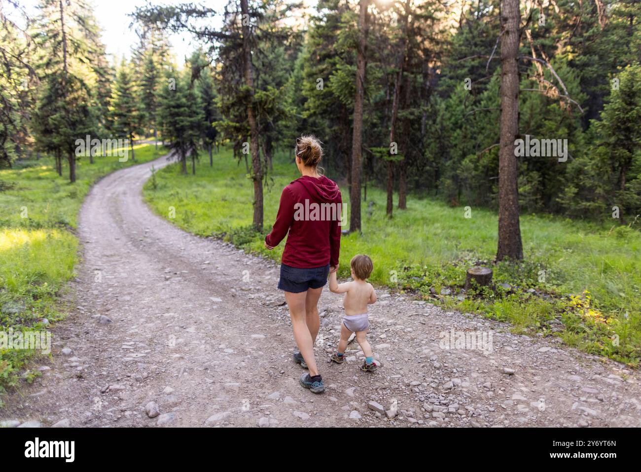 A mother walks down a dirt road with her toddler child Stock Photo - Alamy