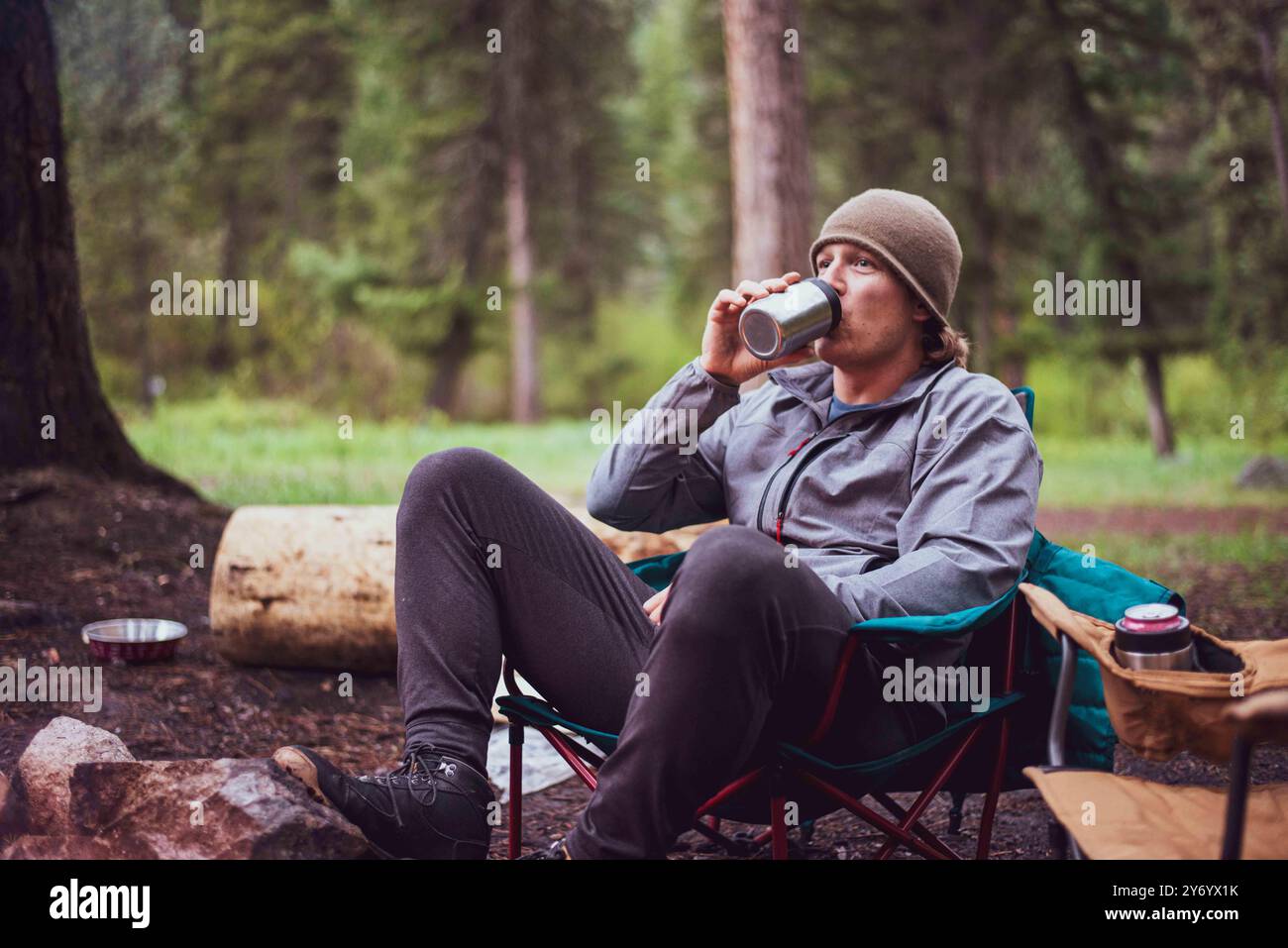 Man sitting in a camp chair around a fire drinking from a can Stock ...