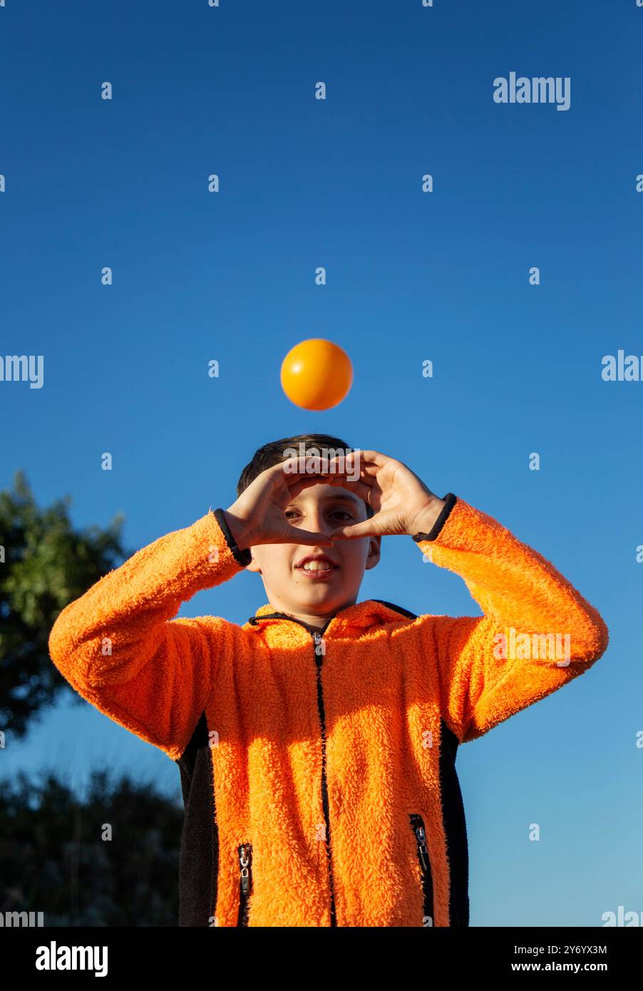 Boy is trying to catch the tossed ball and making frame with hands ...