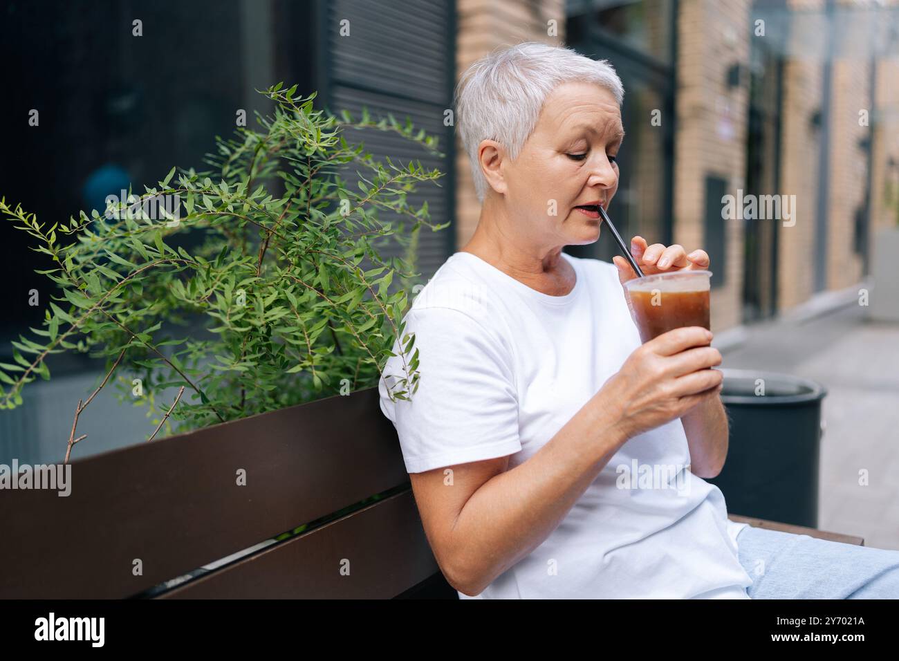 Relaxed senior woman with short gray hair drinking cold juice while ...