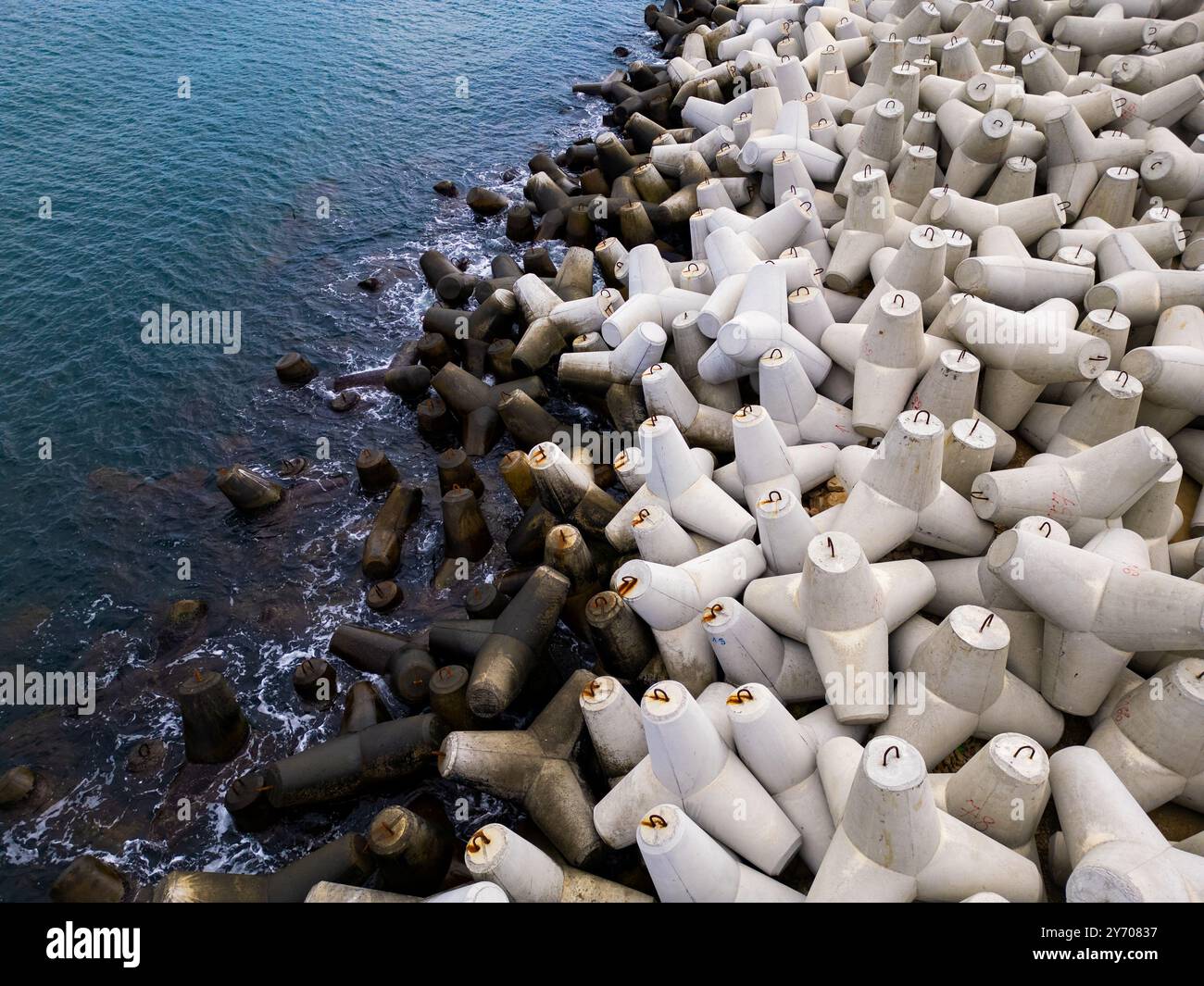 Heavy concrete tetrapods lined along the shoreline at a coastal area ...