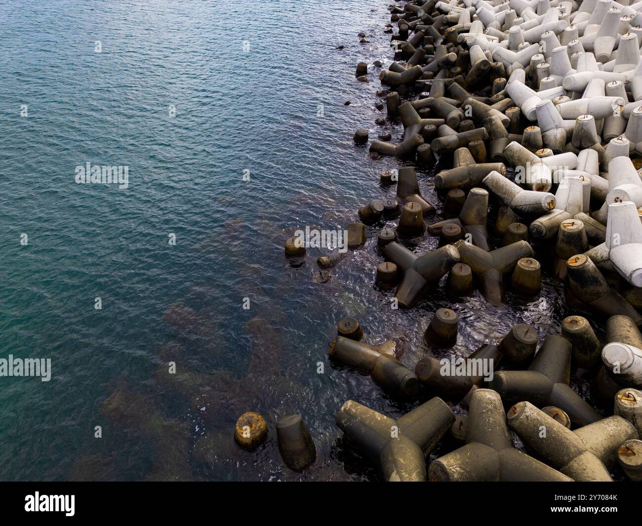 Heavy concrete tetrapods lined along the shoreline at a coastal area ...