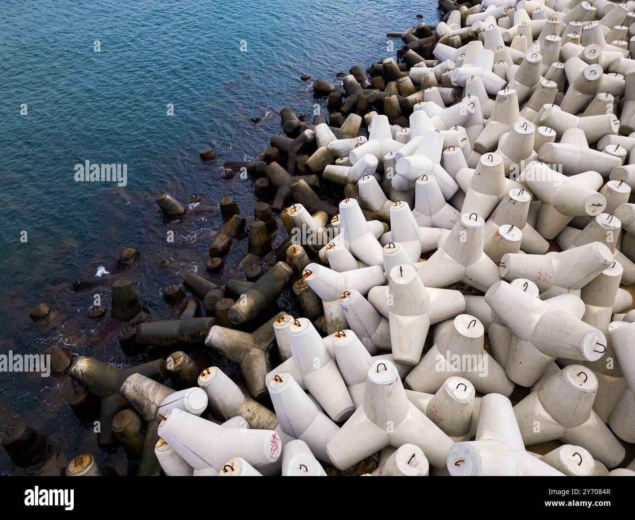 Heavy concrete tetrapods lined along the shoreline at a coastal area ...