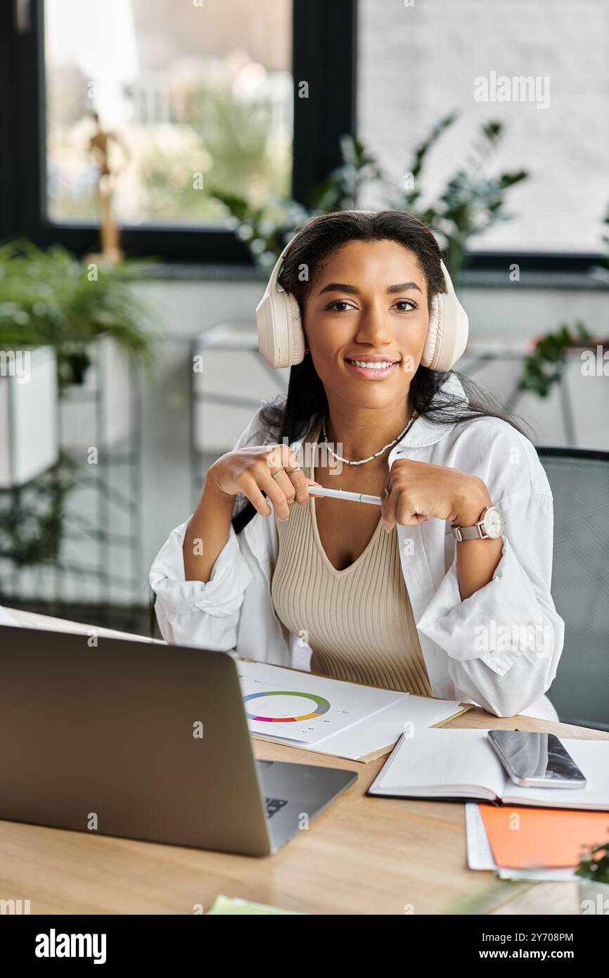 A young beautiful woman smiles warmly while working at her desk ...