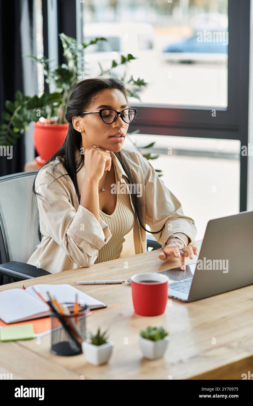 A young woman with glasses works diligently at her desk, showcasing ...