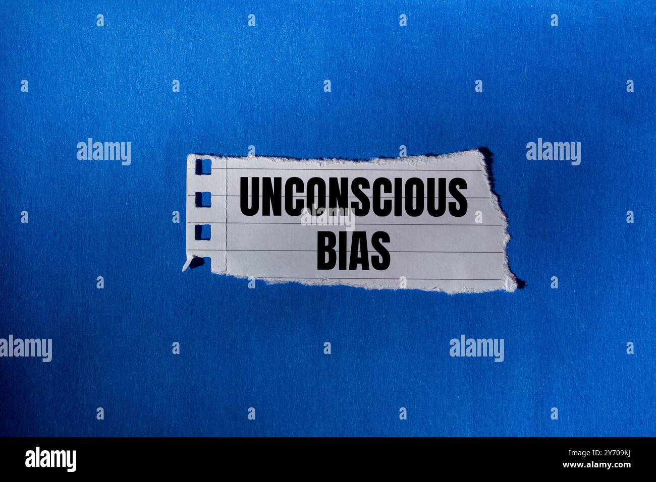 Unconscious bias message written on ripped torn paper piece with blue background. Conceptual ...