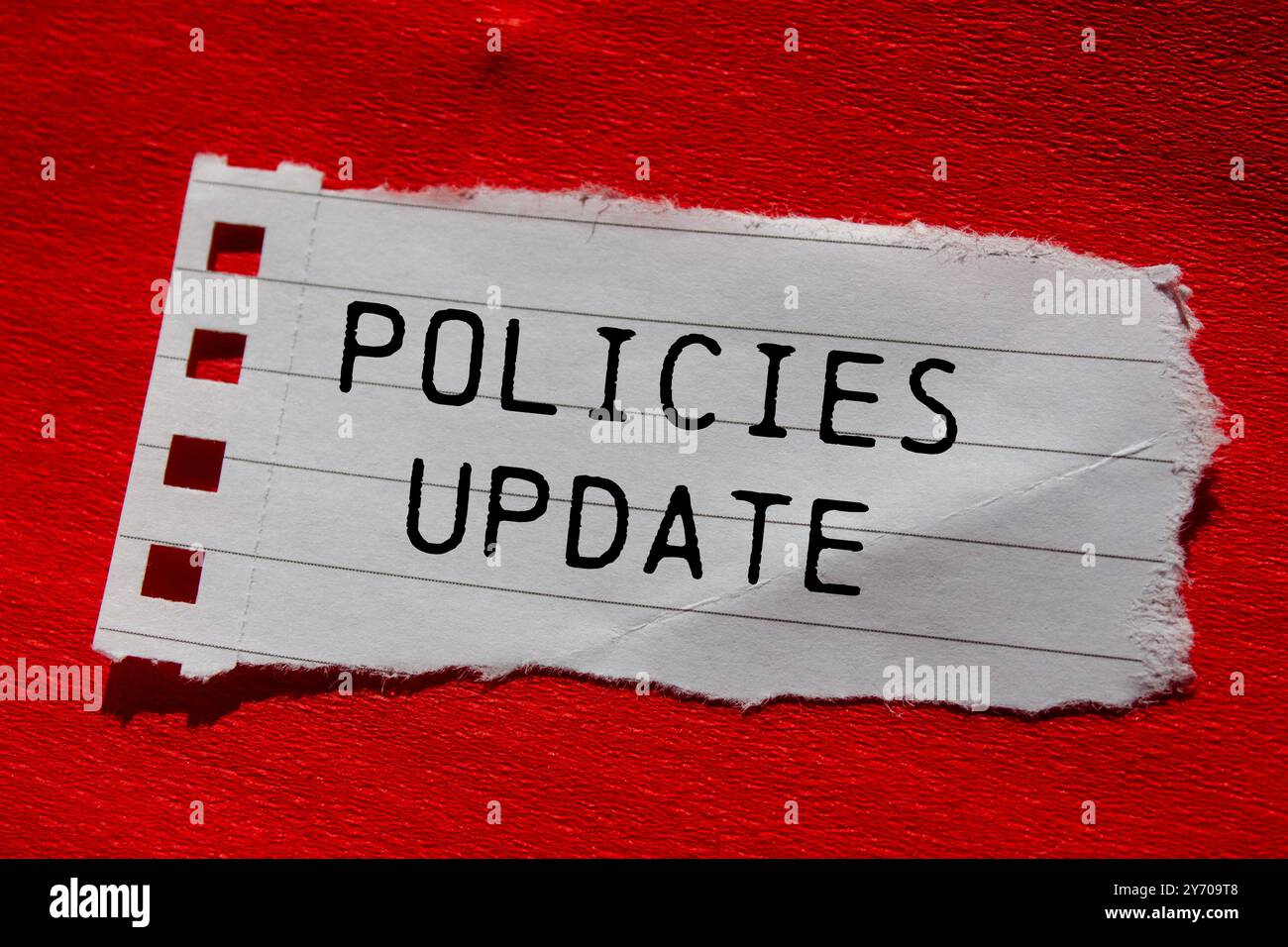 Policies update message written on ripped torn paper piece with red background. Conceptual ...