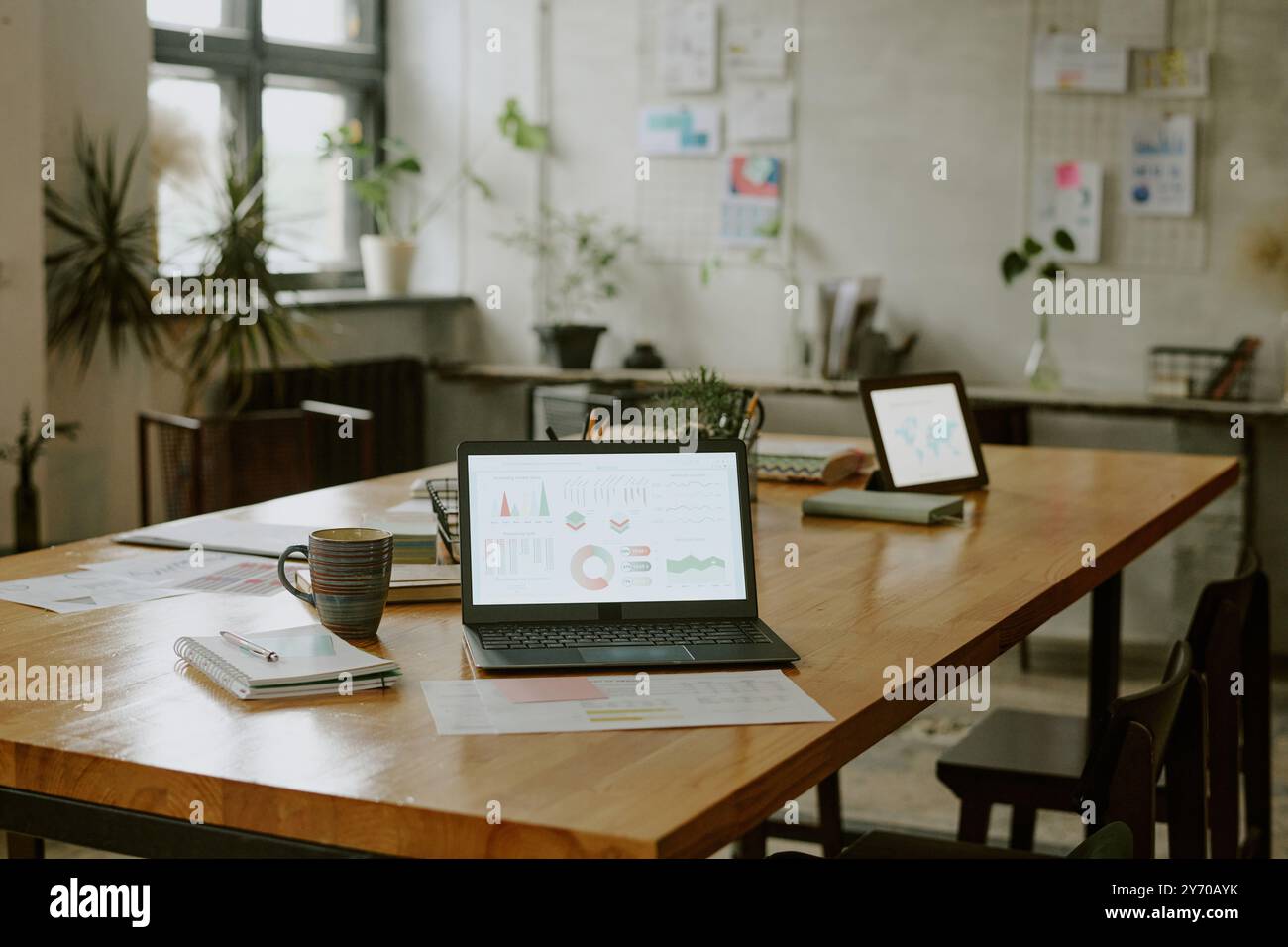 Wooden table with laptop, tablet and paper with diagrams and schemes in ...