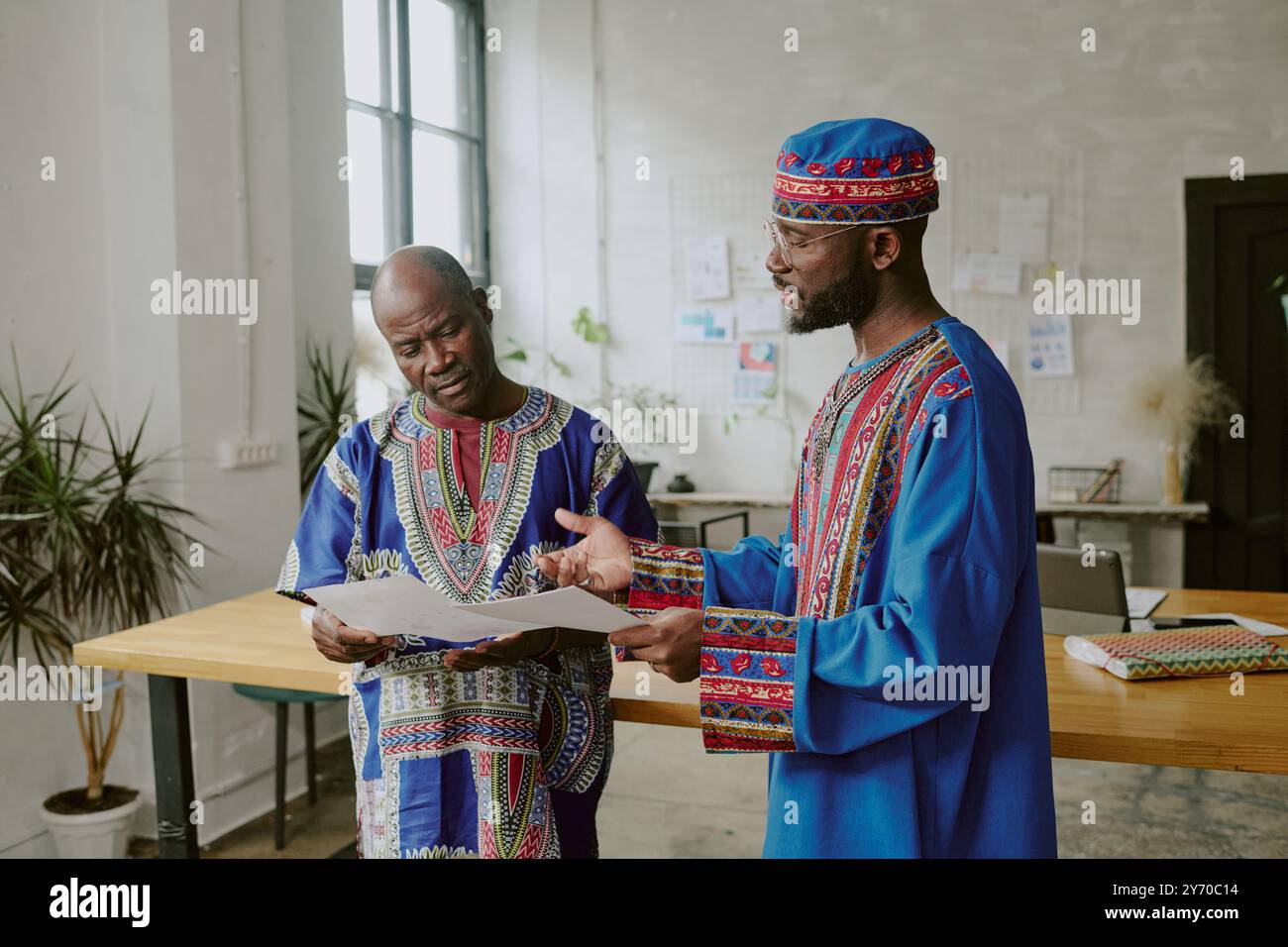 African American coworkers in traditional clothes discussing new ...
