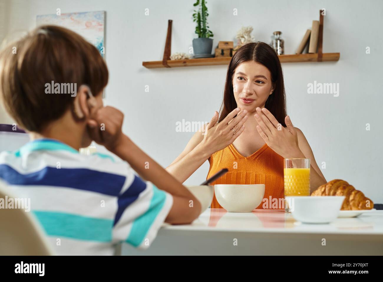 A boy engages with his mother as she uses sign language while they ...