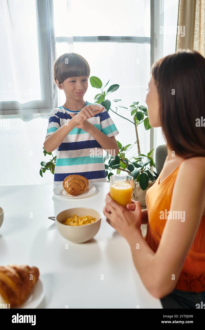 A little boy shares a cheerful breakfast with his mother, enjoying food ...