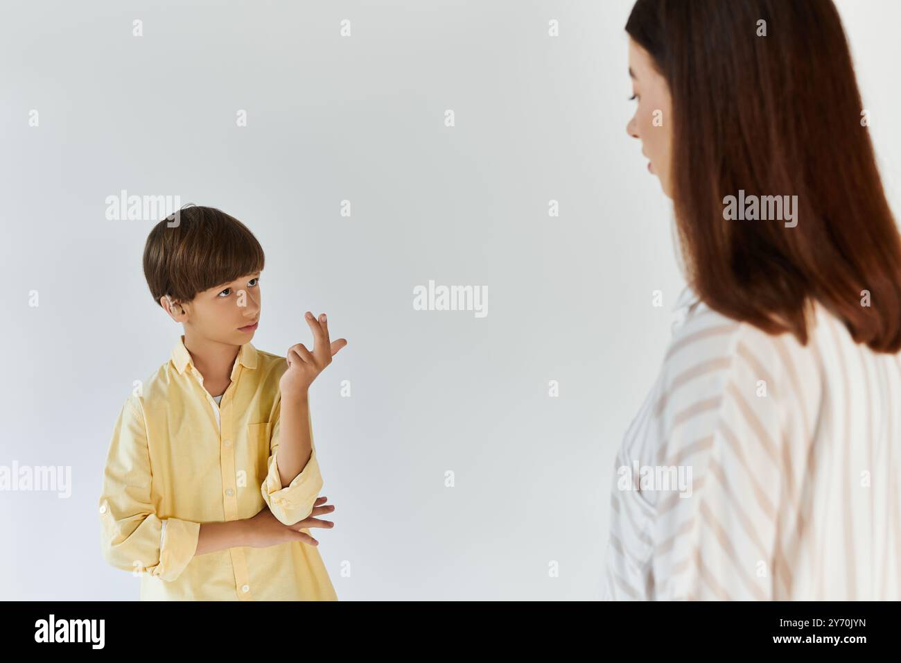 A little boy communicates through sign language, expressing his ...
