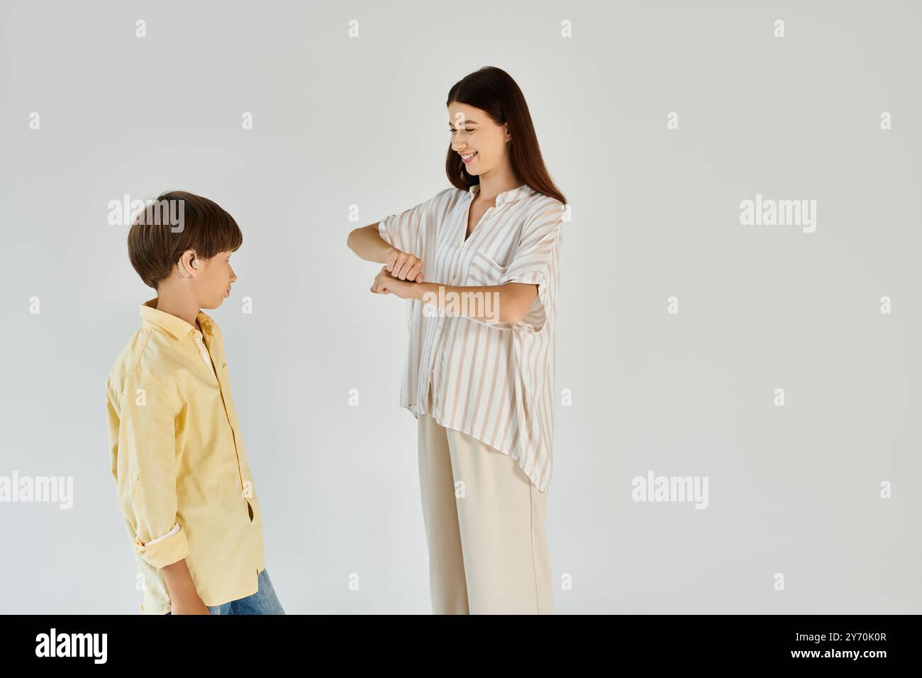 A young boy smiles as his mom gestures to him, fostering understanding ...